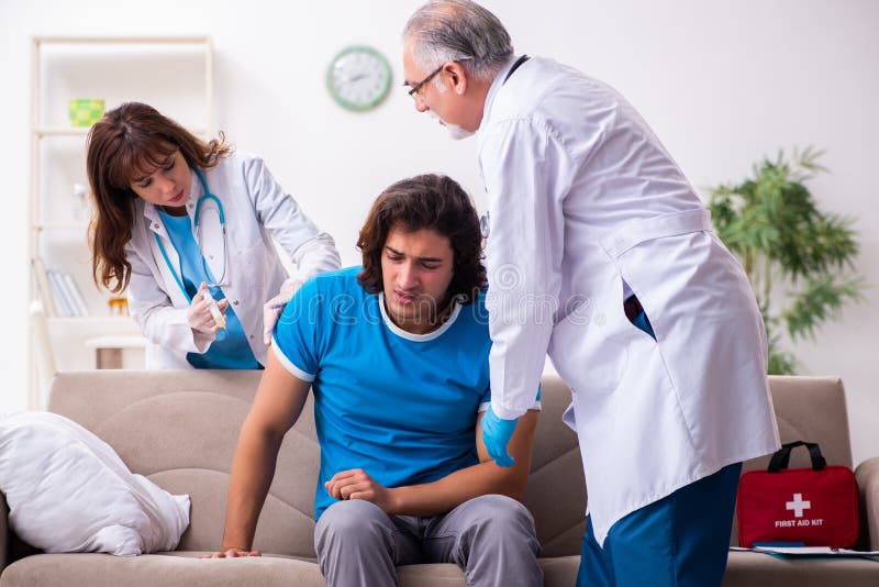 Two Doctors Visiting Sick Young Man at Home Stock Image - Image of ...