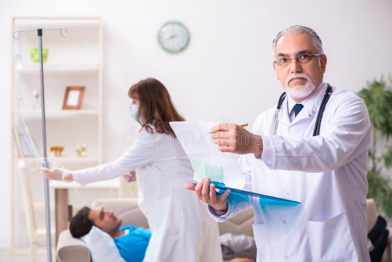 Two Doctors Visiting Sick Young Man at Home Stock Photo - Image of ...