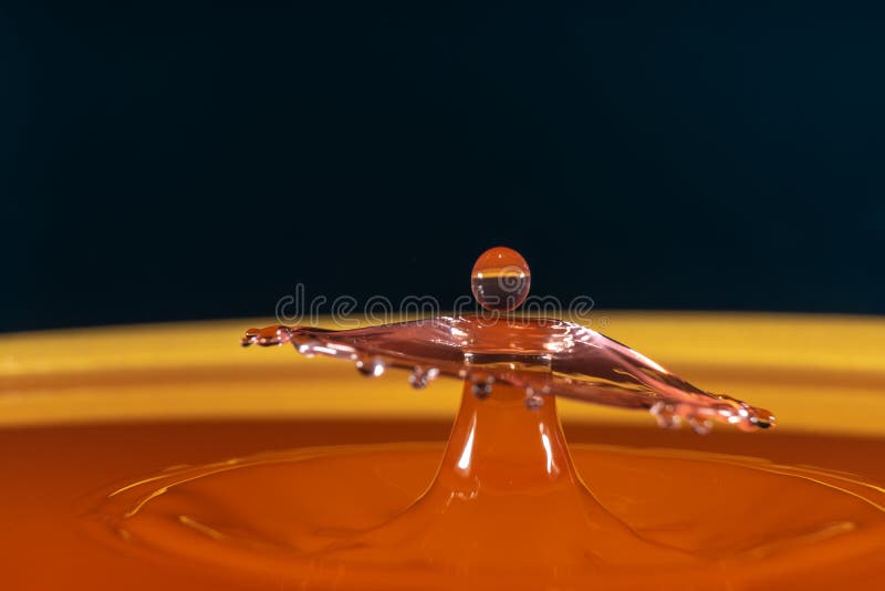 Two Drops of Orange Liquid Fall into the Cup Hitting Each Other Then ...