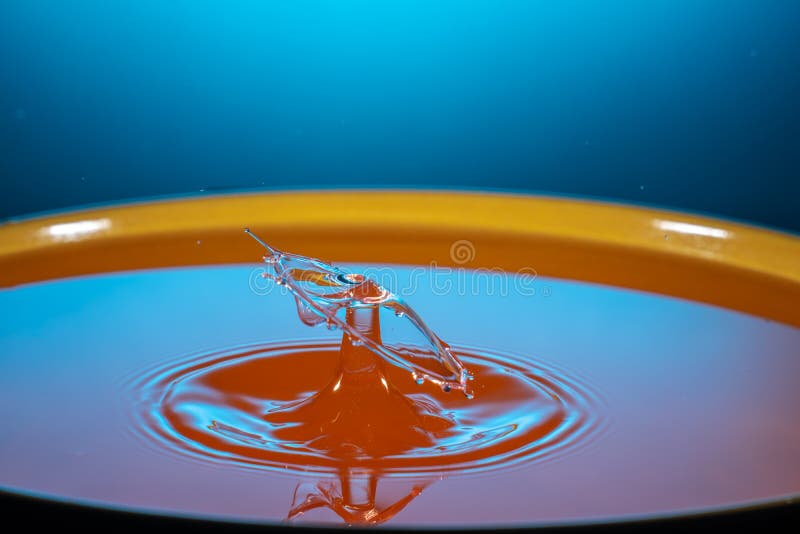 Two Drops of Orange Liquid Fall into the Cup Hitting Each Other Then ...