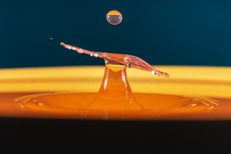 Two Drops of Orange Liquid Fall into the Cup Hitting Each Other Then ...