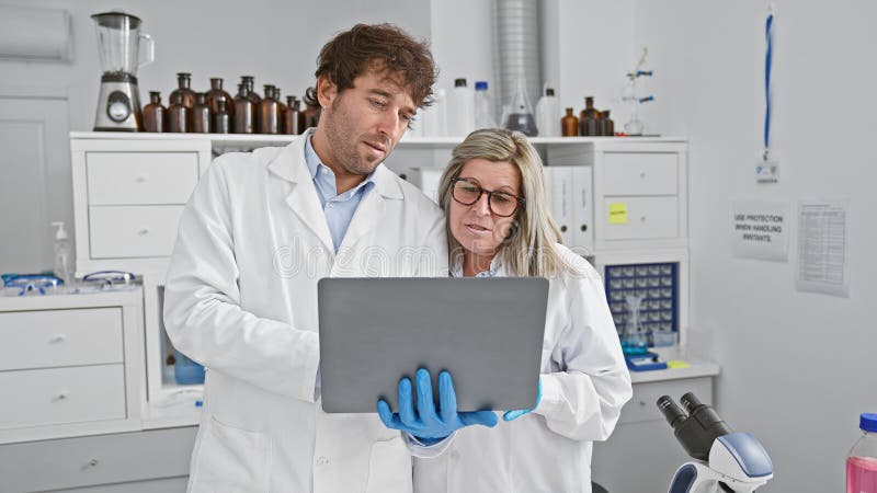 Two Dynamic Scientists, a Man and Woman, Working Together with a Laptop ...