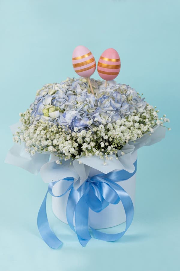 Two Easter Painted Eggs in a Bouquet of Flowers on a Blue Background ...
