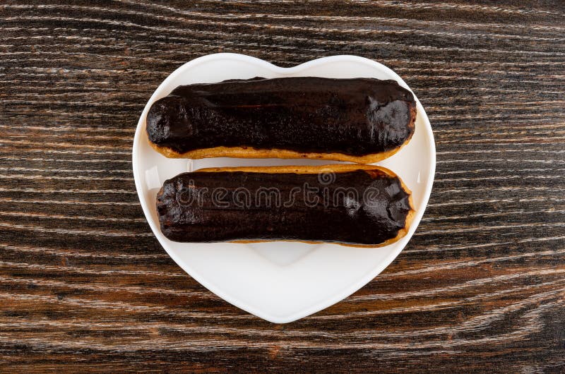 Eclairs with Chocolate Glaze in Plate on Wooden Table. Top View Stock ...