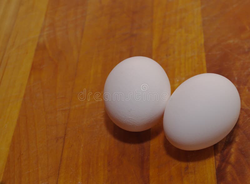 Two Eggs Together on a Wooden Cutting Board Stock Photo - Image of ...