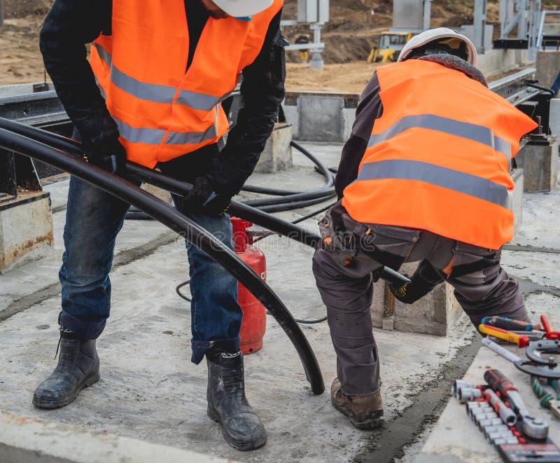 Two Electrician Builder Workers Installing High-voltage Cable Stock ...