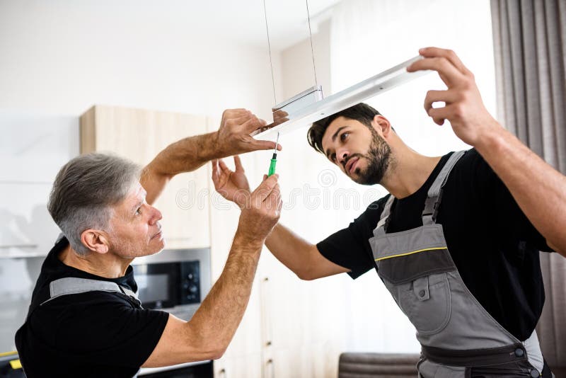 Two Electricians, Workers in Uniform Installing Electric Lamp, Light ...