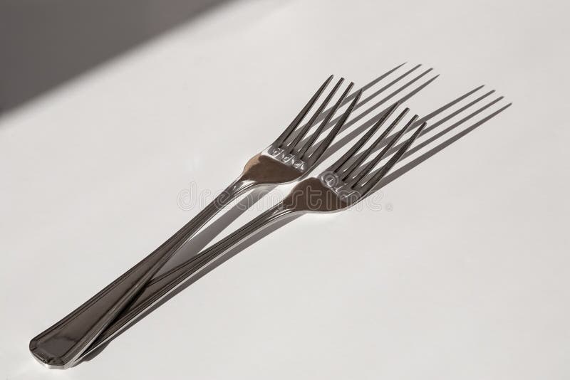 Two Elegant Stainless Forks on White Table with Sharp Sunny Shadow ...