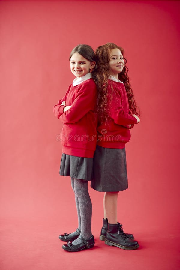 Two Elementary School Pupils Wearing Uniform Back To Back Against Red ...