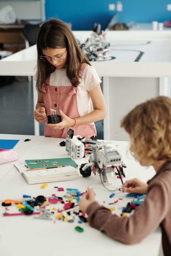 Two Elementary Schoolkids Standing by Table with Details of Robot at ...