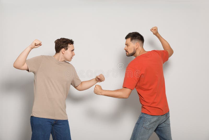 Two Emotional Men Fighting on Light Blue Background Stock Photo - Image ...