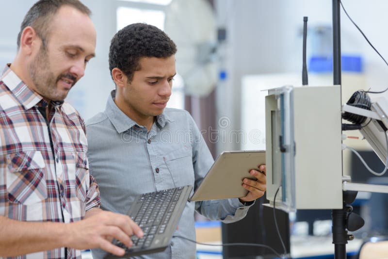 Two Employees Using Tablet and Computer Keyboard in Workshop Stock ...