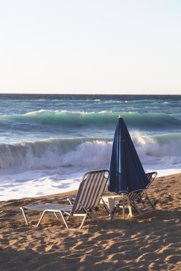 Two Empty Sunbeads, Closed Blue Umbrella on Sandy Beach with the Big ...