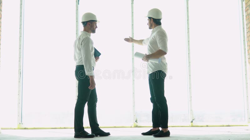 Two Engineer with a Drawing in Hand Looking at the Construction Site ...