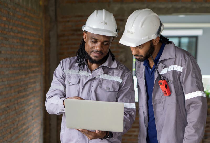 Two Engineer in Hardhat Examine a Laptop Together at a Construction ...