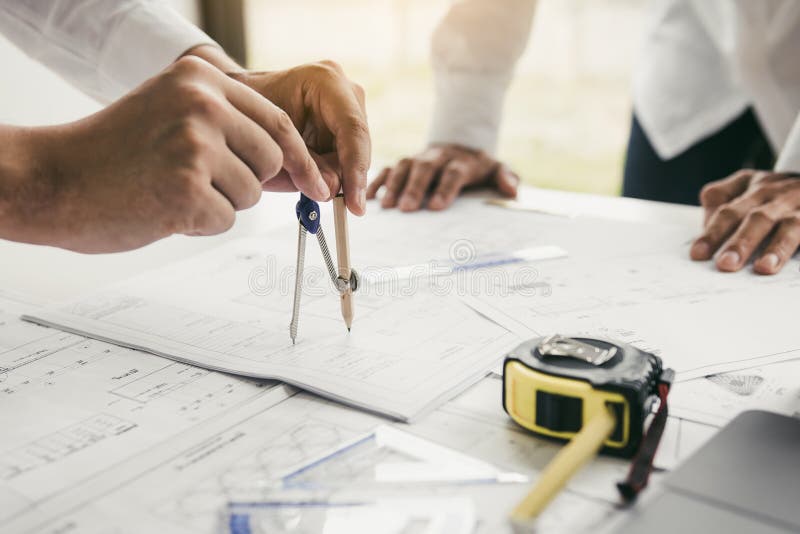 Two Engineering Working Together and Using Compass Looking Blueprint ...