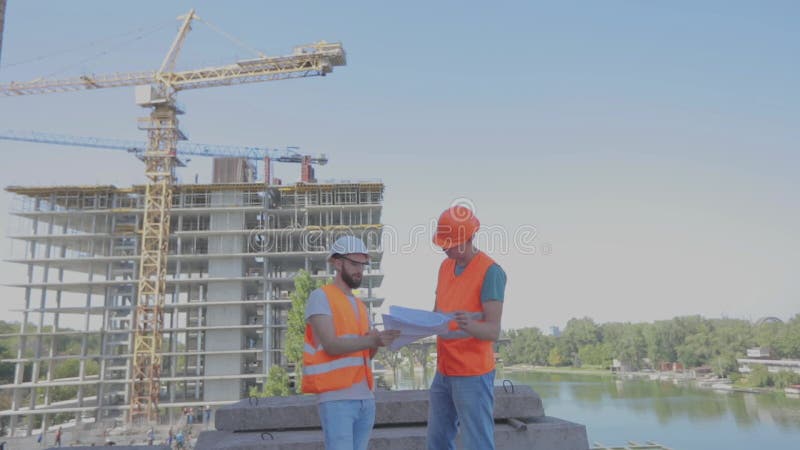 Two Engineers at a Construction Site are Looking at the Drawing ...