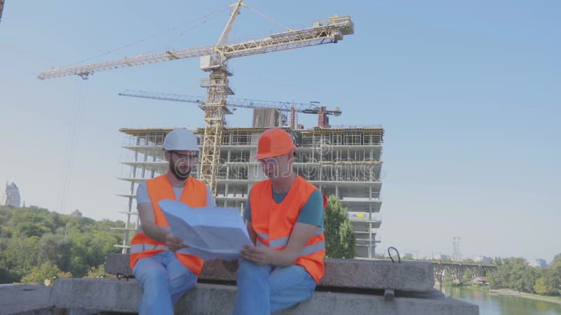 Two Engineers at a Construction Site are Looking at the Drawing ...