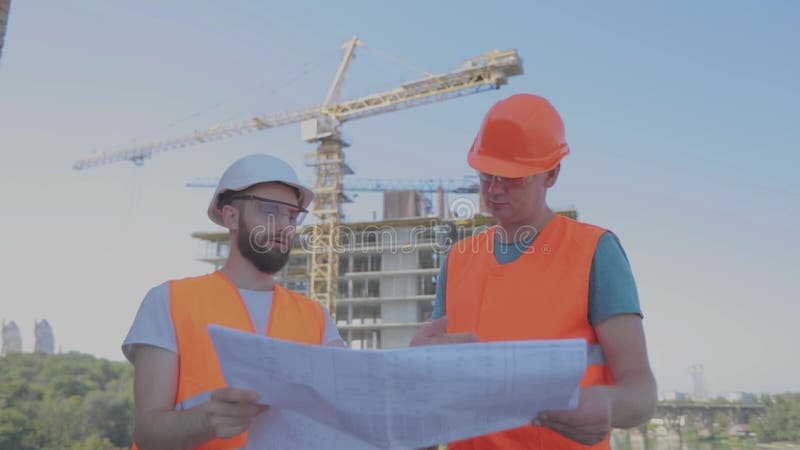 Two Engineers at a Construction Site are Looking at the Drawing ...