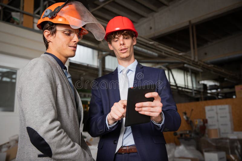Two Engineers Discuss a Project Using a Tablet while they are in the ...