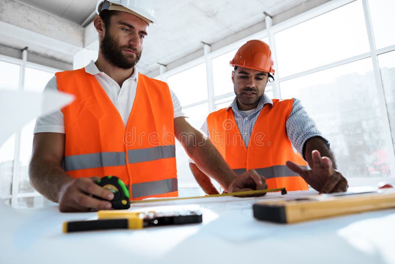 Two Engineers Man Looking at Project Plan on the Table in Construction ...