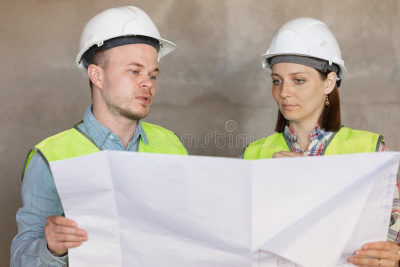 Two Engineers, a Man and a Woman in White Helmets and Protective Vests ...