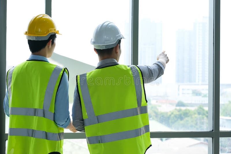 Two Engineers Man Standing in Front of Windows. Left Engineer Holding ...