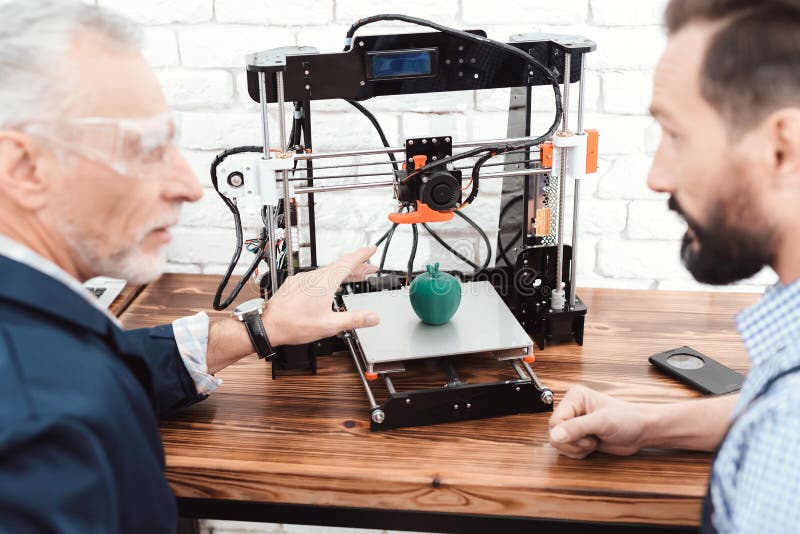 Two Engineers are Printing an Apple Model on a 3d Printer. they Look at ...