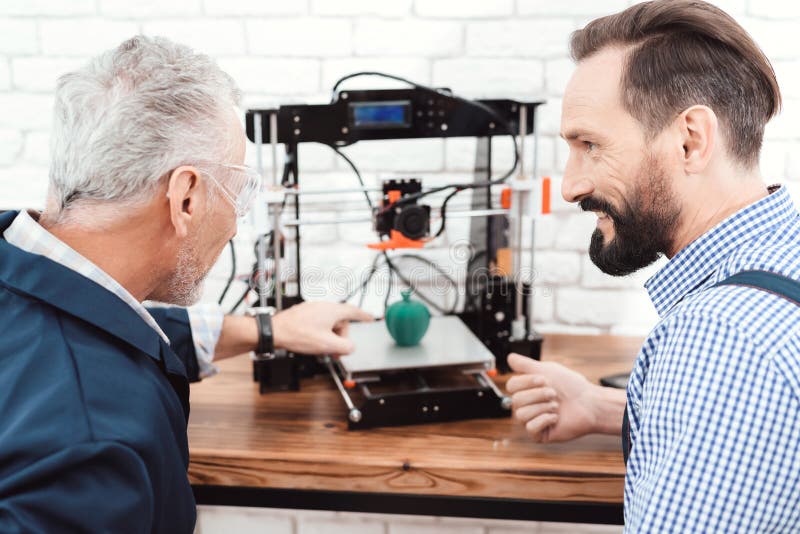 Two Engineers are Printing an Apple Model on a 3d Printer. they Look at ...