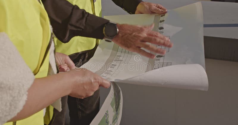 Engineers Collaborate on Building Plans at a Construction Site ...