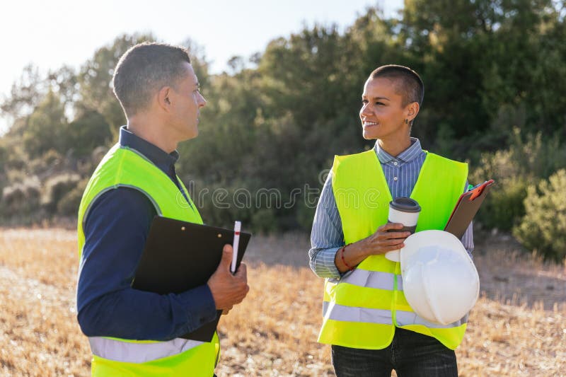 Two Engineers Talking while Working Together Outdoors in the Field ...