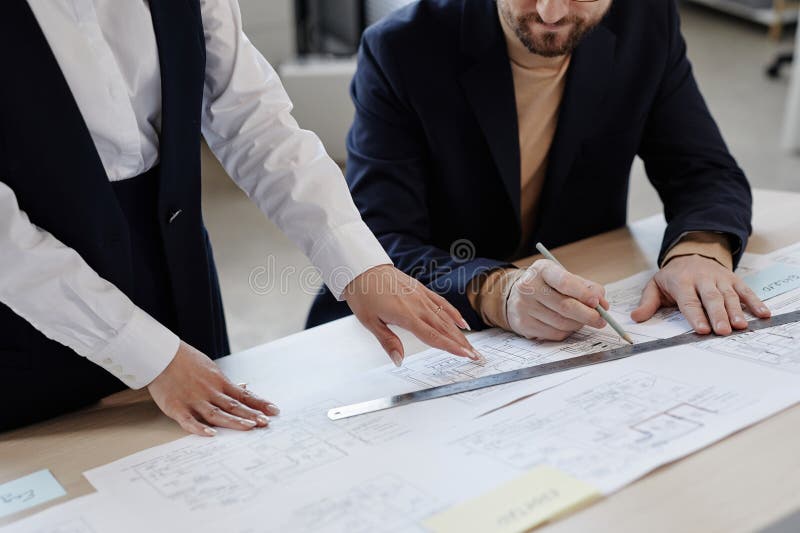 Two Engineers at Workstation Drawing Blueprints and Plans and Doing ...