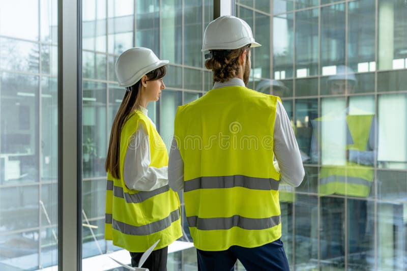 Two Engineers in Yellow Vests Standing at the Panoramic Window Stock ...