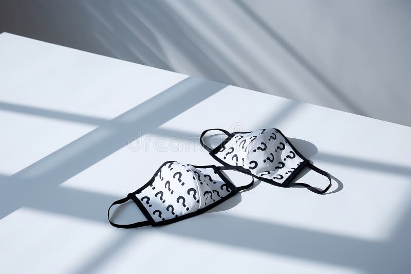 Two Face Masks Printed with Question Marks Lie on a Sunlit White ...