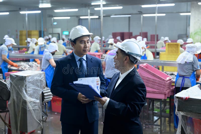 Two Factory Managers in Safety Helmets Discussing Documents Inside a ...
