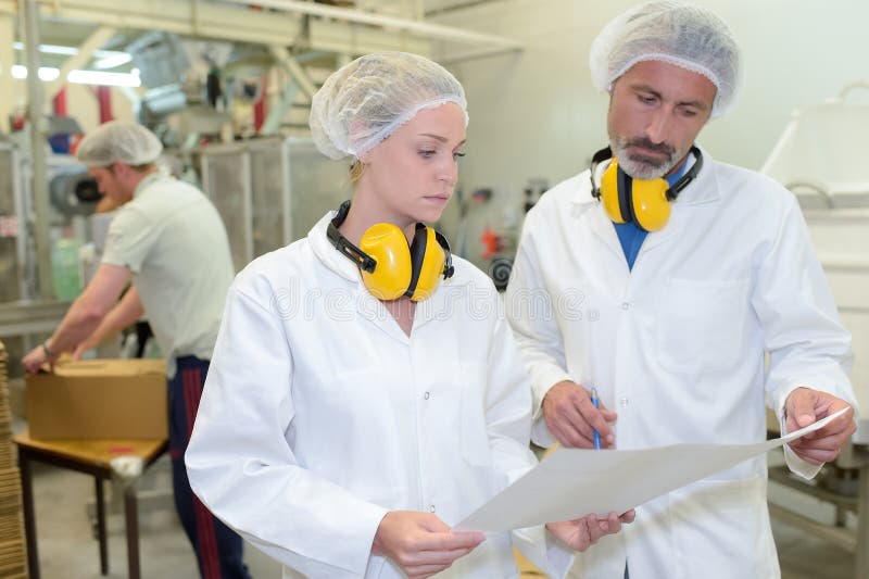 Two Factory Workers Looking at Paperwork Stock Image - Image of women ...