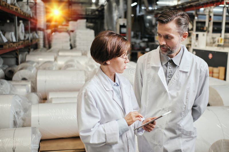 Two Factory Workers in White Robe with Tablet Standing in the Warehouse ...