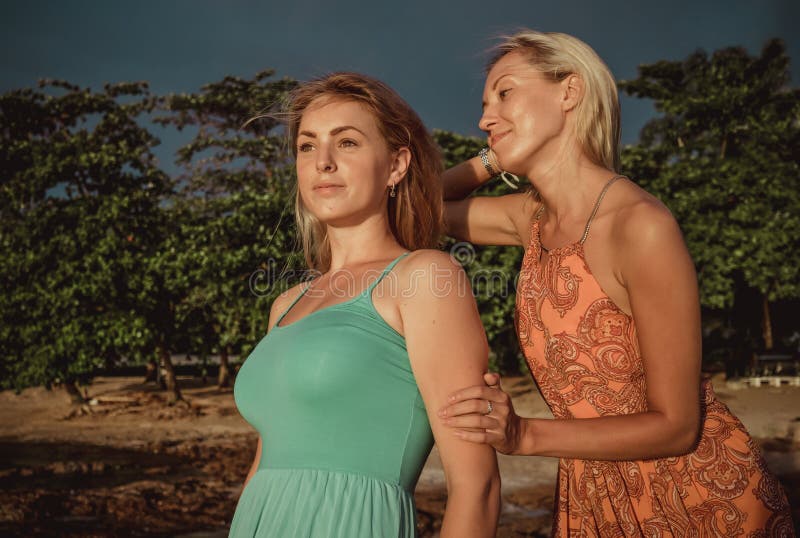 Two Fashion Models Posing in Red and Turquoise Dresses in the Rays of ...