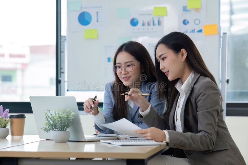 Two Female Accountant Collaborating on Financial Graphs and Data ...