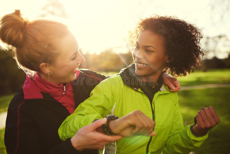 Two Female Athletes Smiling and Hugging after Workout in Park Stock ...