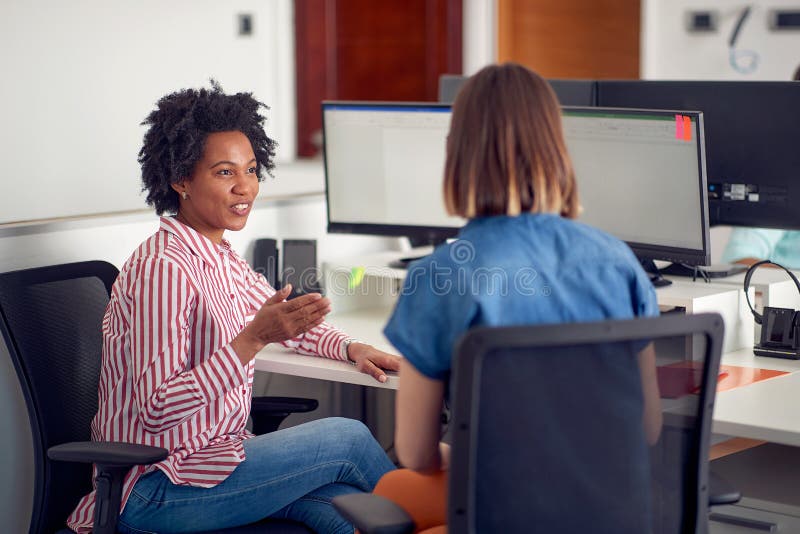 Two Female Coworkers Consulting Together in the Office Stock Photo ...