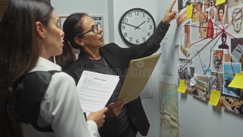 Two Female Detectives Analyze Evidence in an Office with a Board of ...