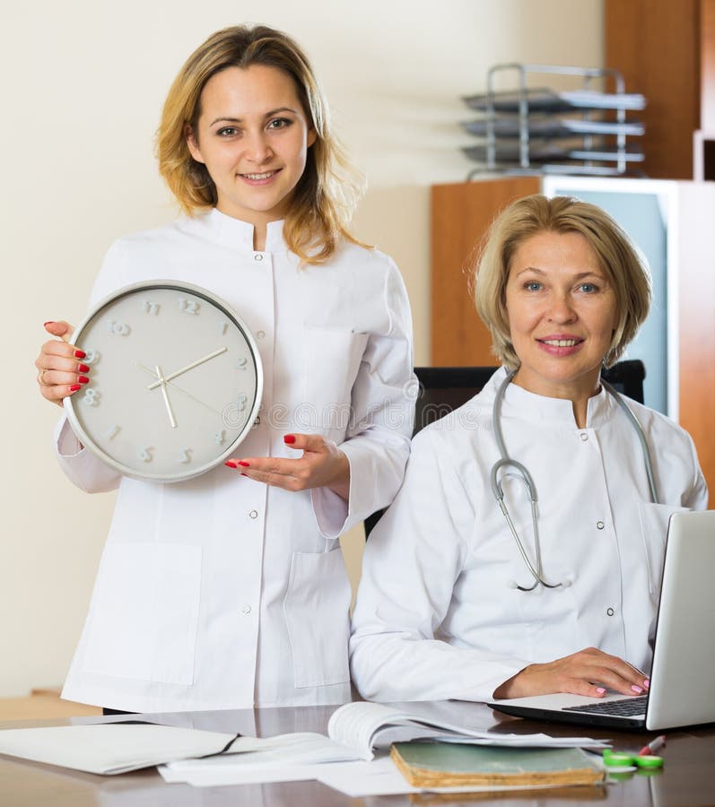 Two Female Doctors Showing Time in Clock Stock Photo - Image of adults ...