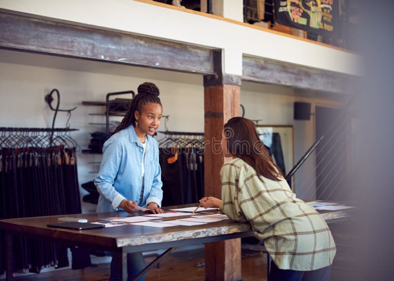 Two Female Fashion Designers Having Creative Meeting Around Wooden ...