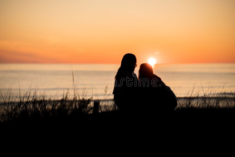 Two Female Friends Enjoying a Conversation while Watching the Sunset on ...