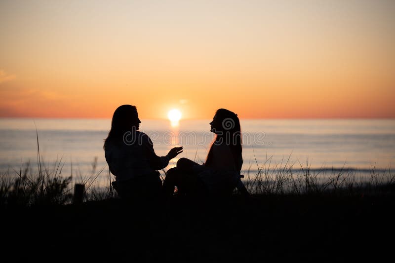 Two Female Friends Enjoying a Conversation while Watching the Sunset on ...