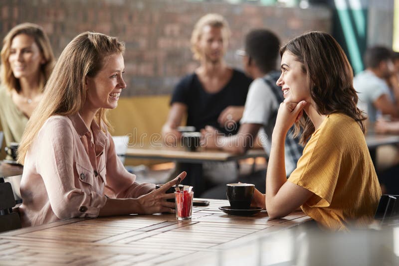 Two Female Friends Sitting at Table in Coffee Shop and Talking Stock ...