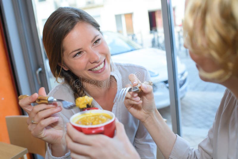 Two Female Friends Talking at Cafe Table and Smiling Stock Photo ...