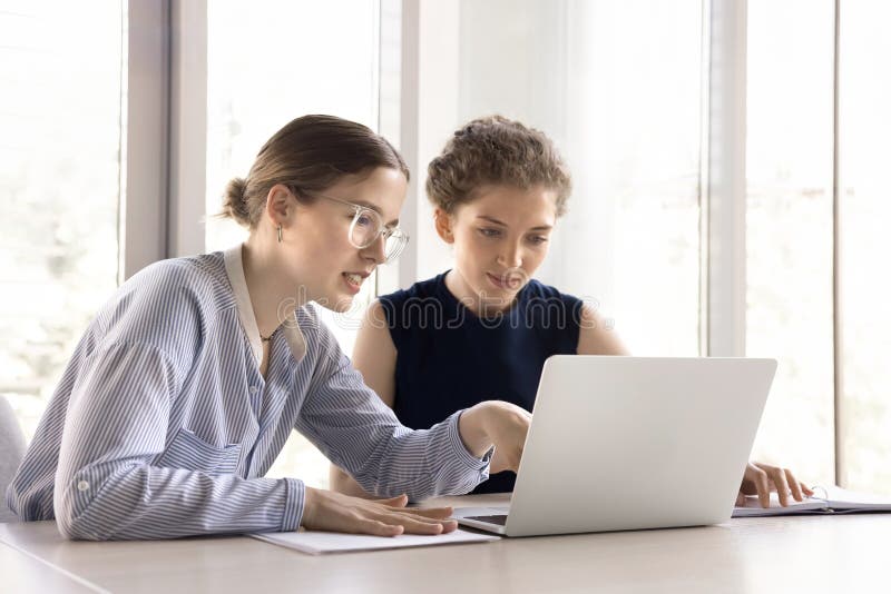 Two Female Office Employees Working Together Using Laptop Stock Photo ...