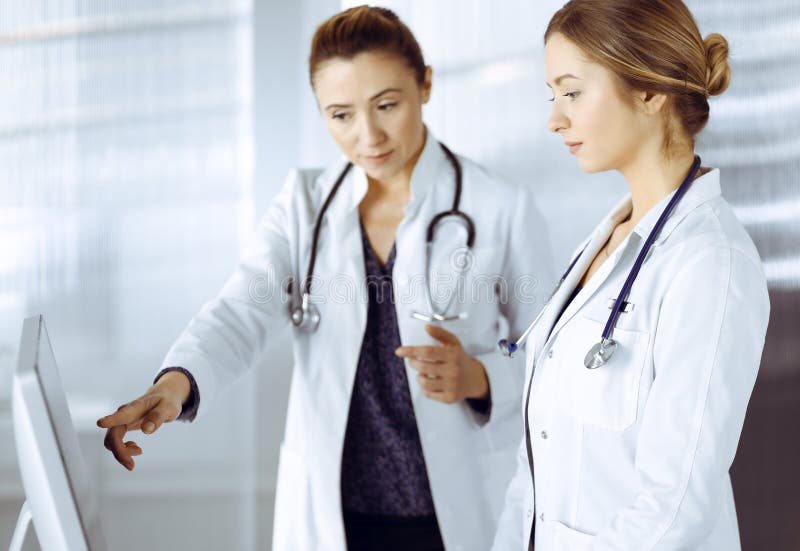 Two Female Physicians are Discussing Medical Therapy, while Standing at ...